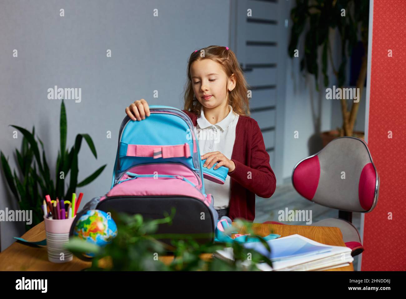 Schoolgirl put books and notes into backpack at home, pupil prepare ...