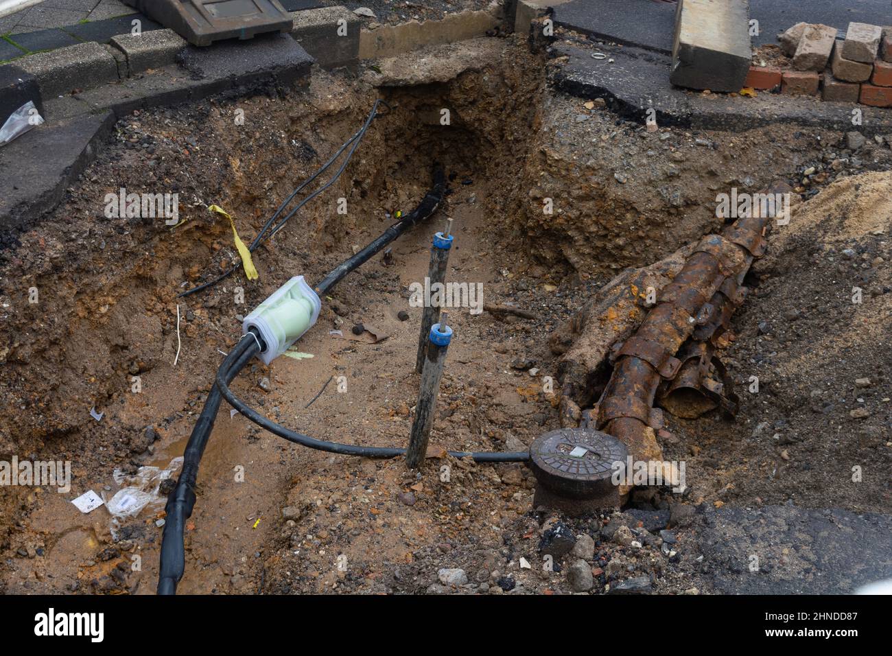 Dug up sidewalk revealing wires in protective tubes. Building of ...