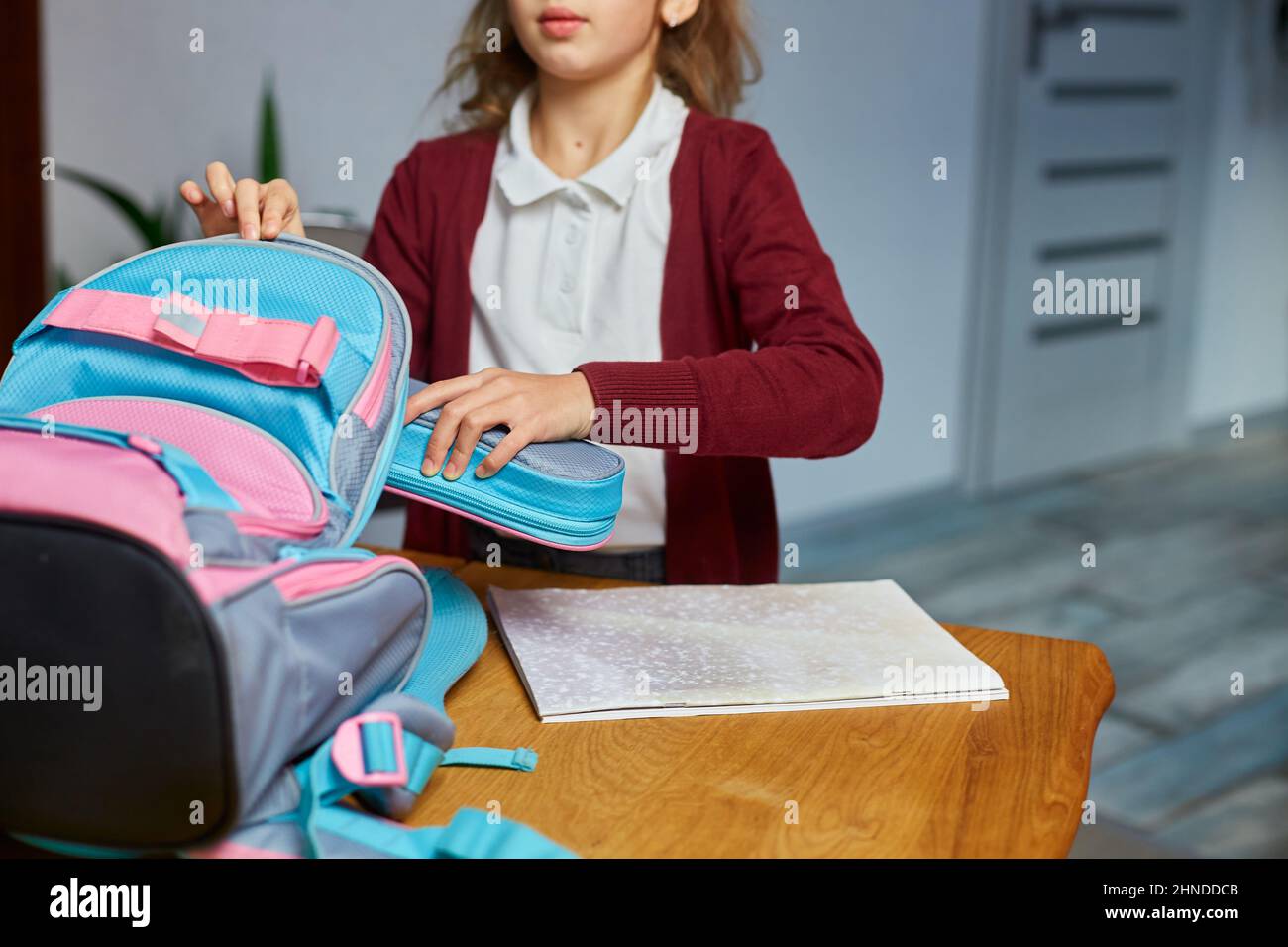 Schoolgirl put books and notes into backpack at home, pupil prepare ...