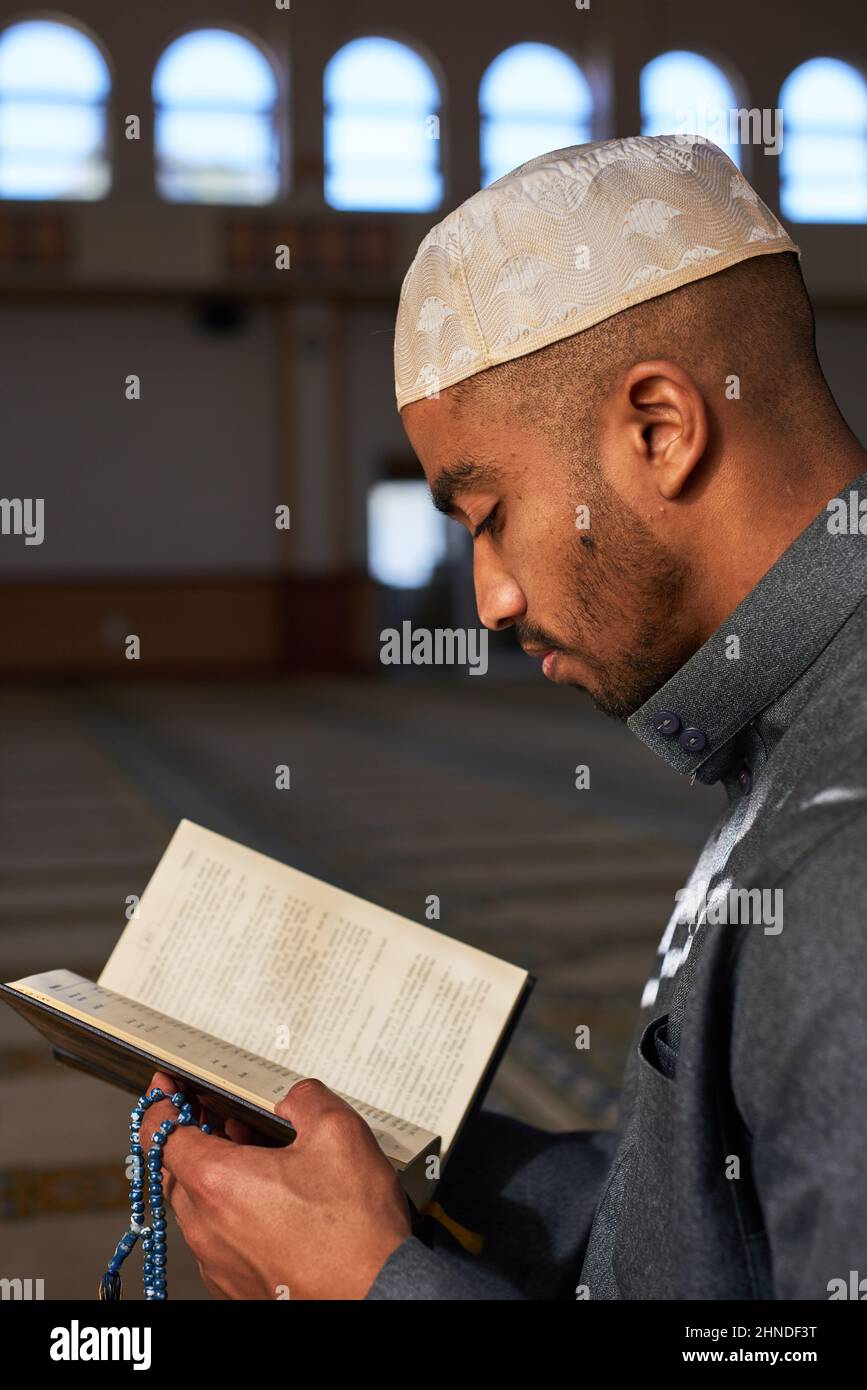 Side view of young Muslim male smiling and reading the Quran Stock ...