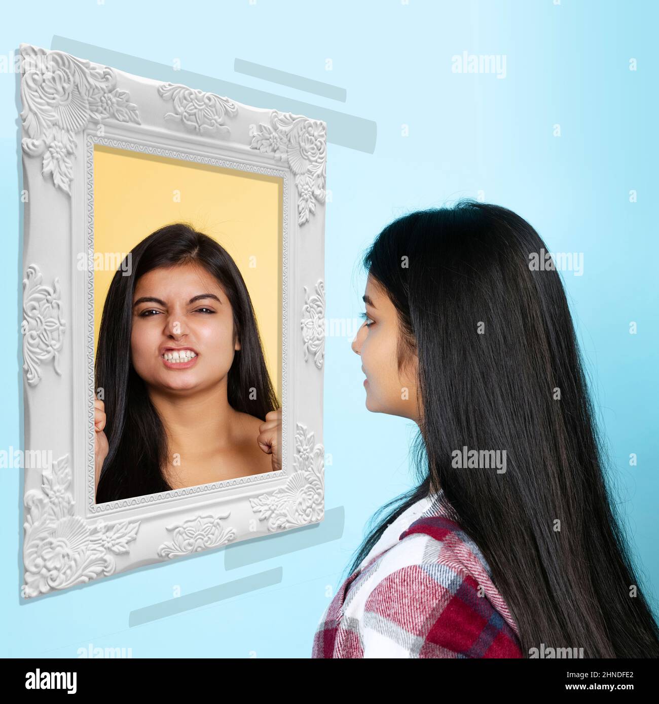 Internal aggression. Young girl looking at mirror isolated on light ...