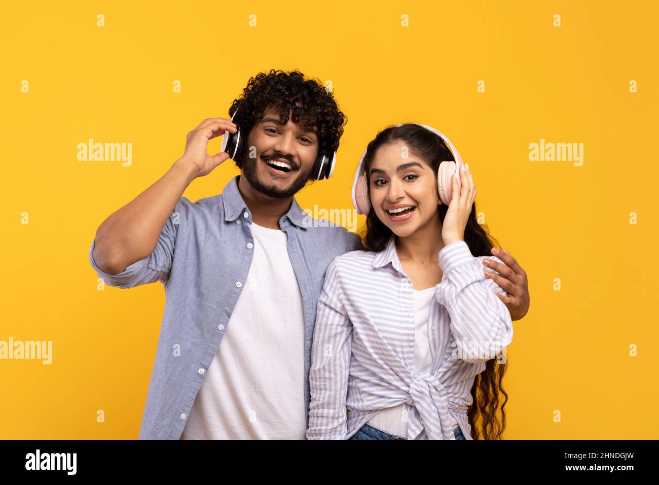Happy indian couple in headphones listening to music and hugging over ...
