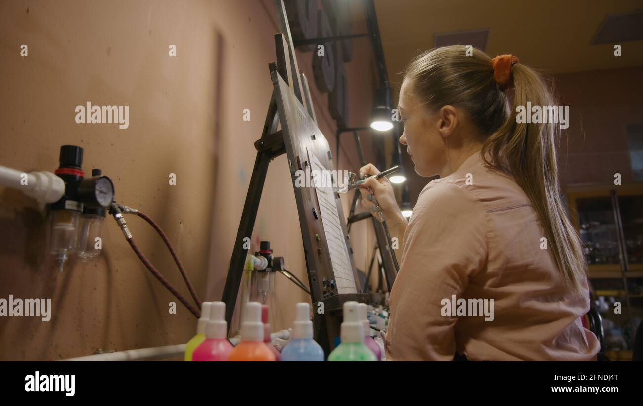 Woman artist learns to paint with airbrush with acrylic dye, paper and ...