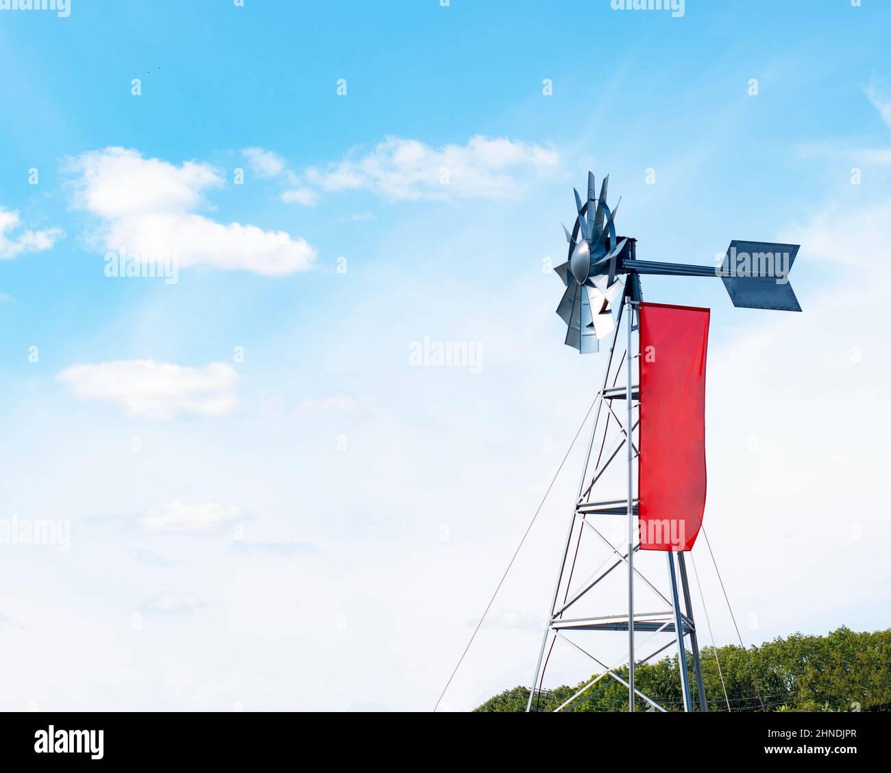 Windmill weather vane with red flag on blue sky background Stock Photo ...