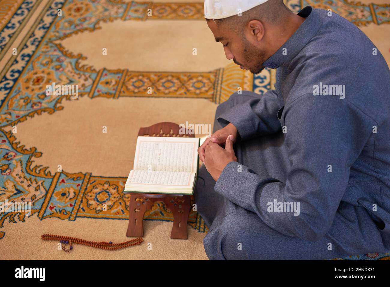 Side view of a young Muslim male reading the Quran inside a mosque ...