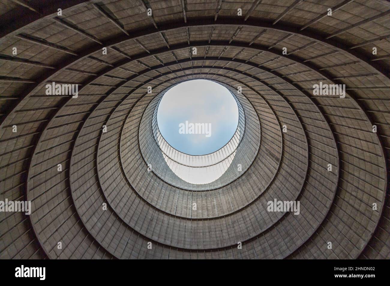 Inside a cooling tower of a nuclear power plant. View upwards, blue sky ...