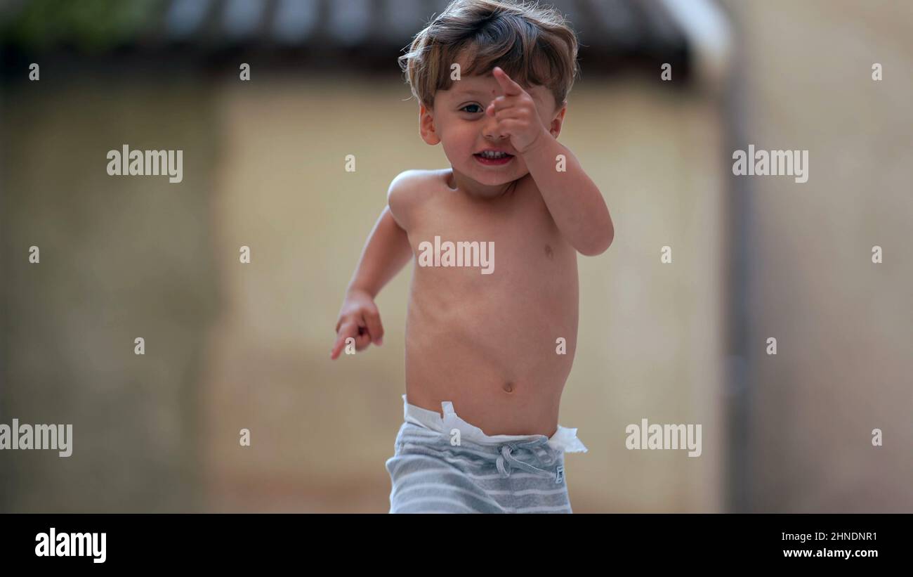 Cute little boy running outside towards camera Stock Photo - Alamy