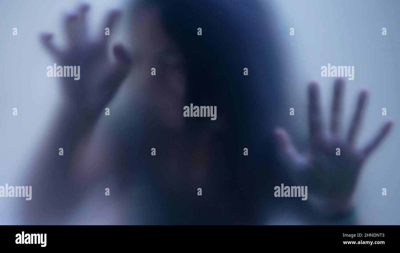 Defocused shot of person trapped in emotional problems behind glass ...