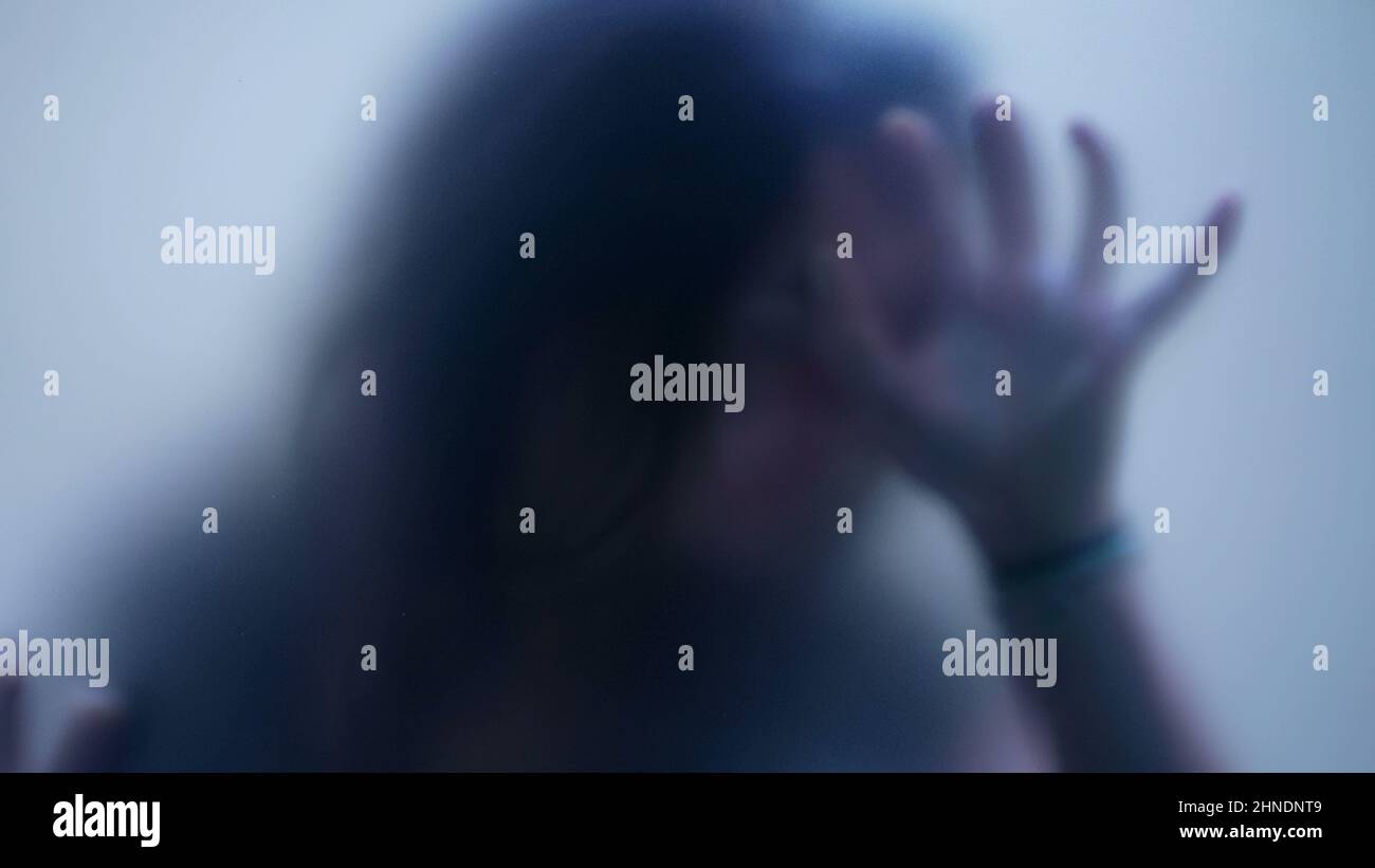 Defocused shot of person trapped in emotional problems behind glass ...