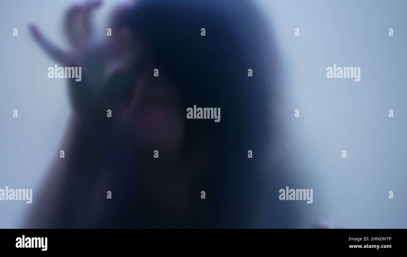 Defocused shot of person trapped in emotional problems behind glass ...