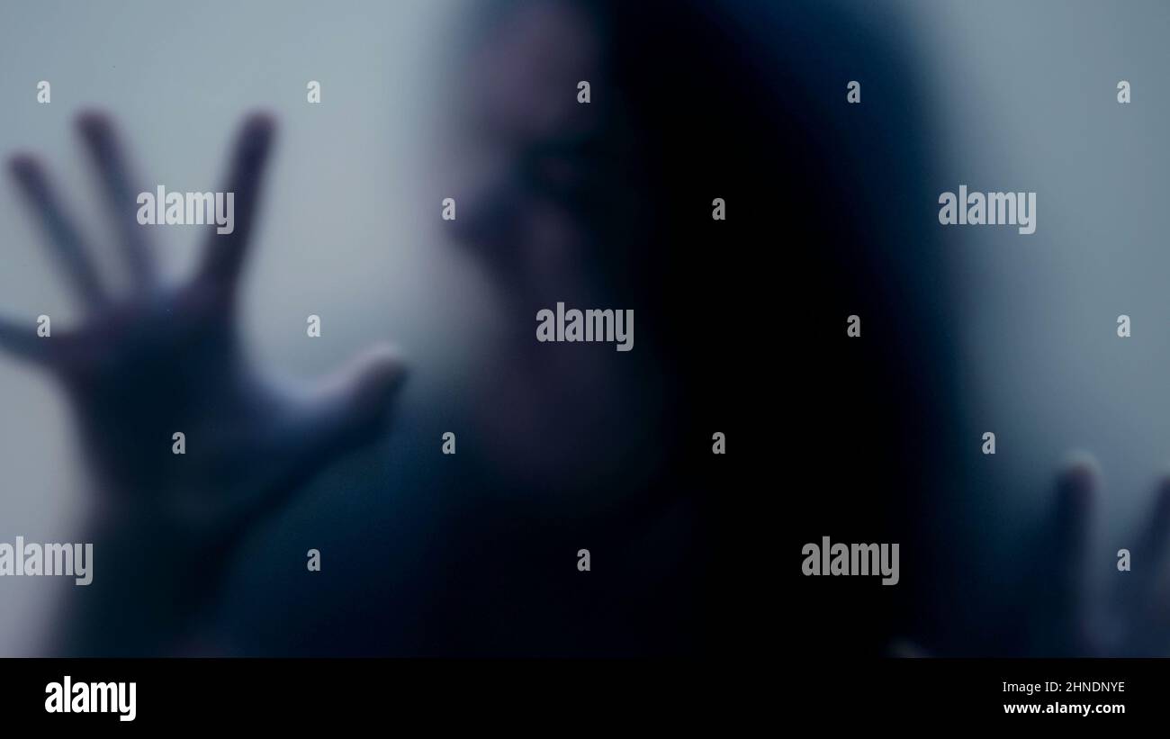 Defocused shot of person trapped in emotional problems behind glass ...