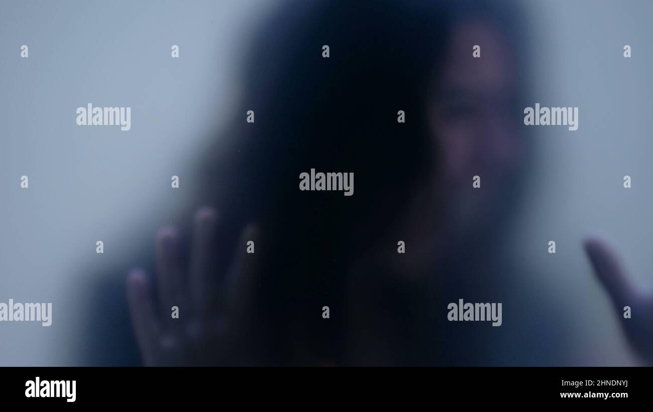 Defocused shot of person trapped in emotional problems behind glass ...