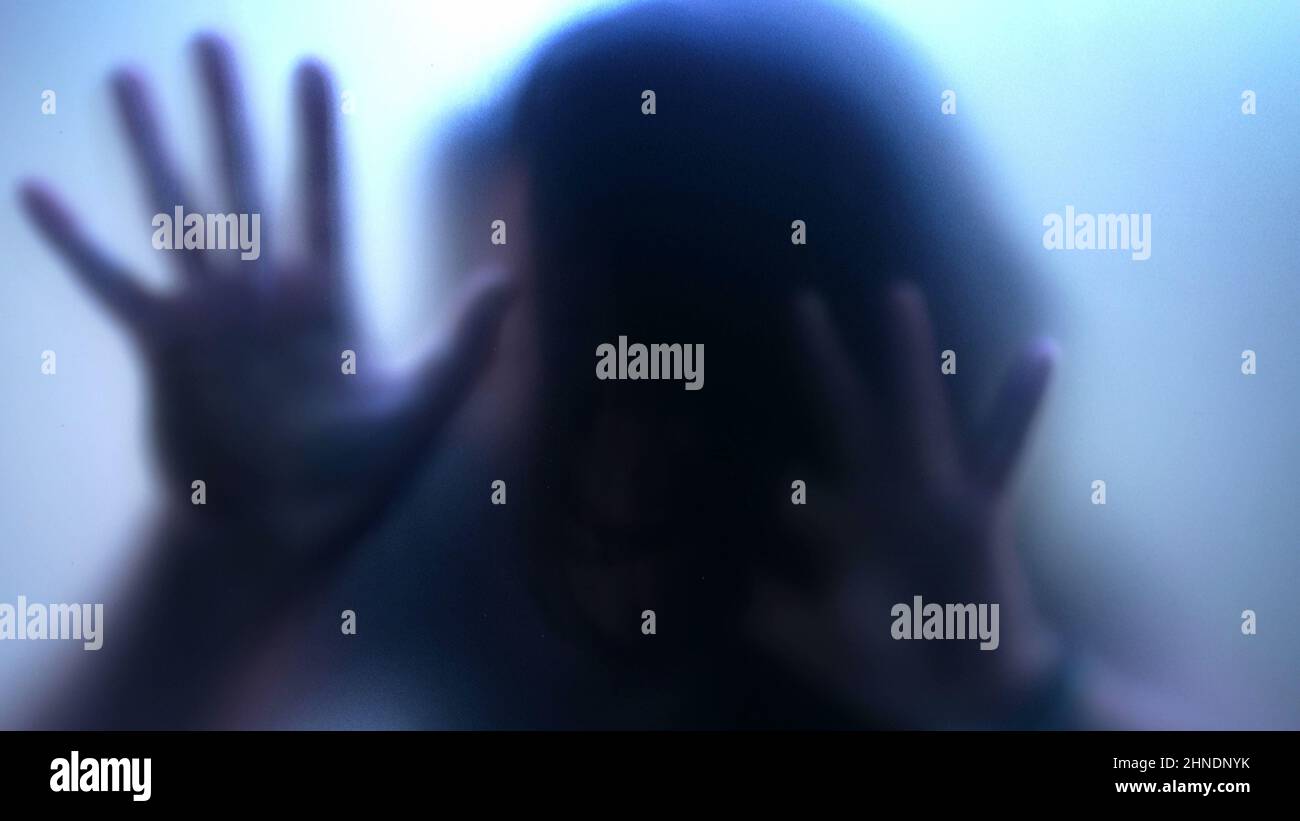 Defocused shot of person trapped in emotional problems behind glass ...