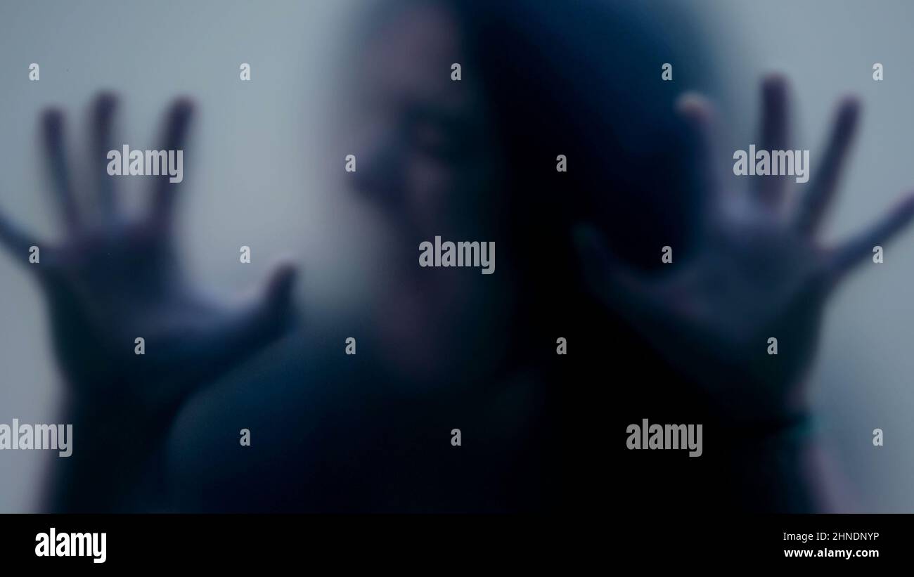 Defocused shot of person trapped in emotional problems behind glass ...