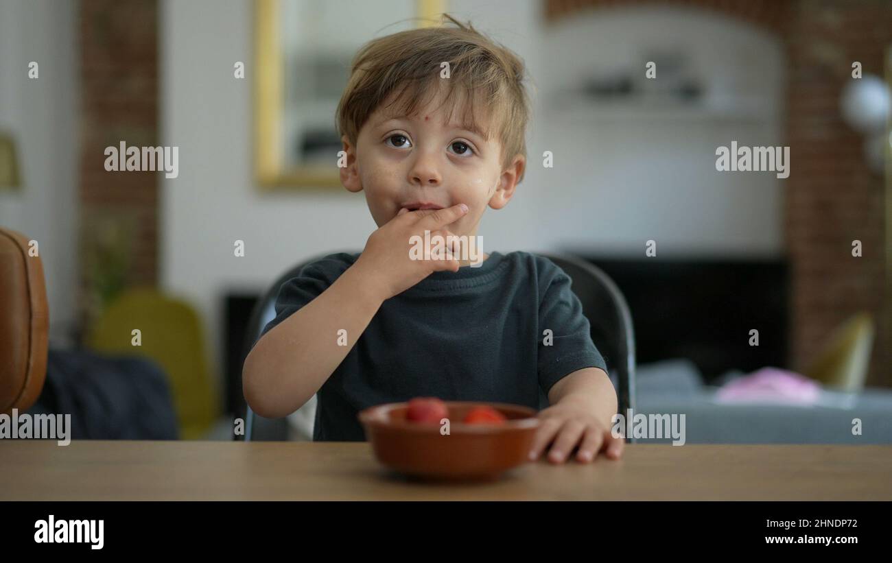 Little boy grabbing food from bowl Stock Photo - Alamy