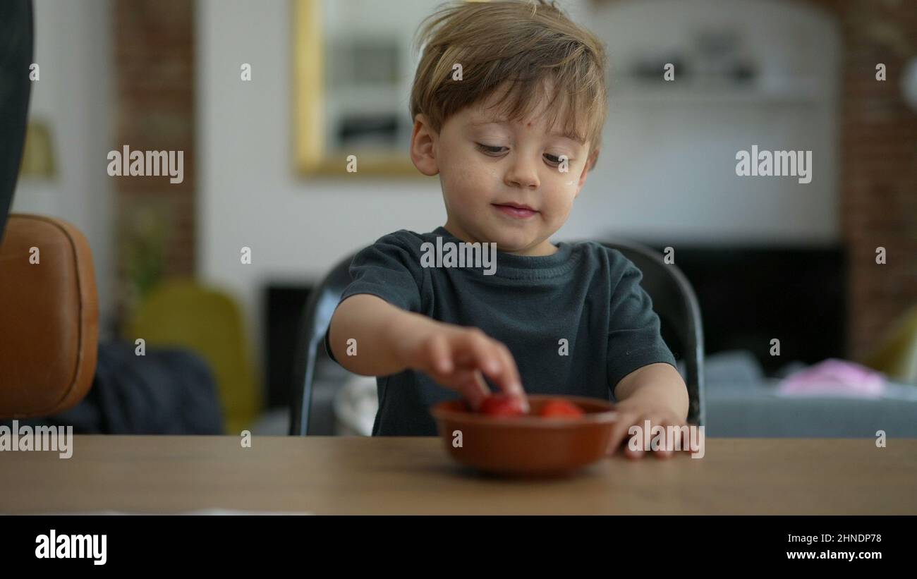 Little boy grabbing food from bowl Stock Photo - Alamy