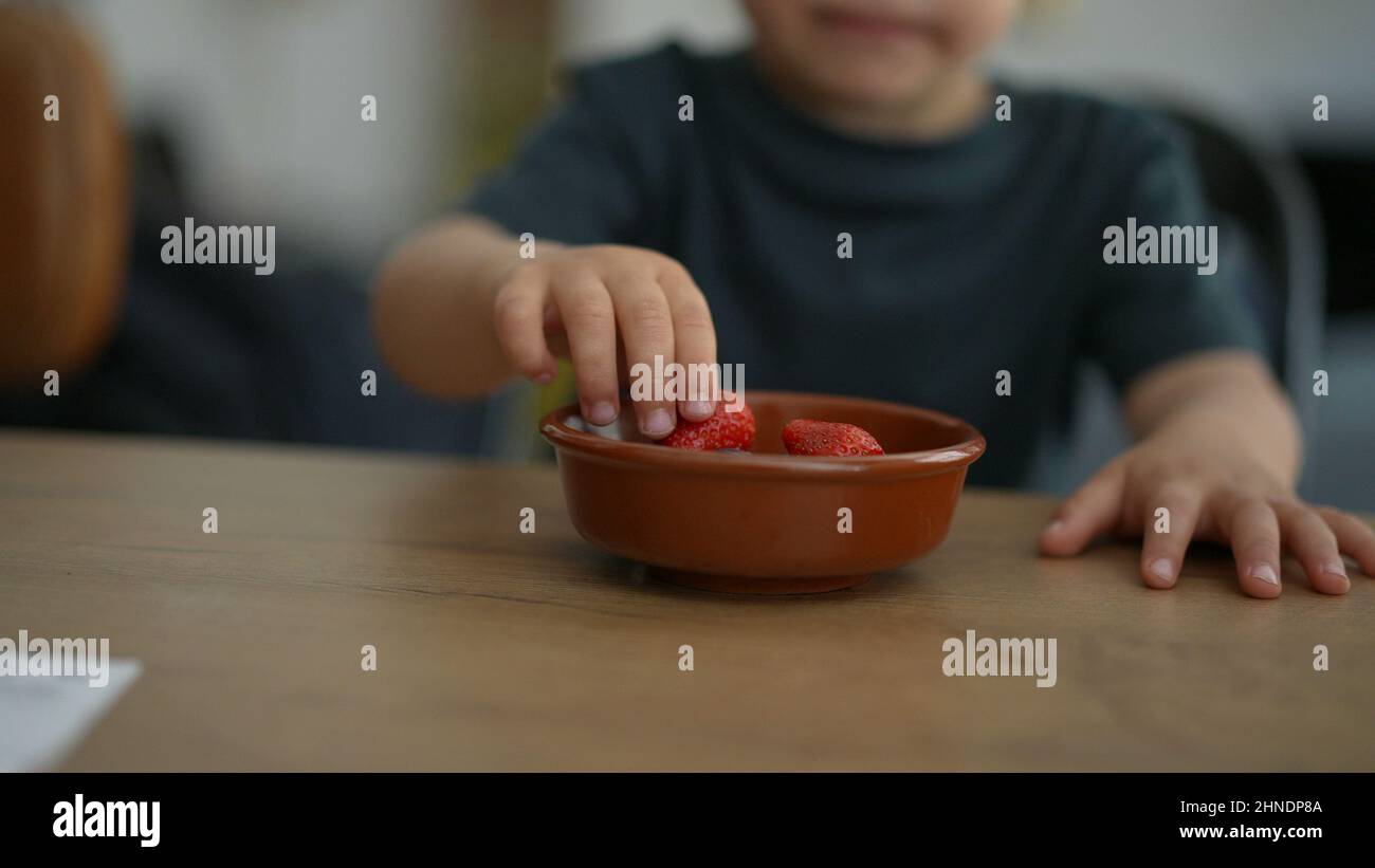 Little boy grabbing food from bowl Stock Photo - Alamy