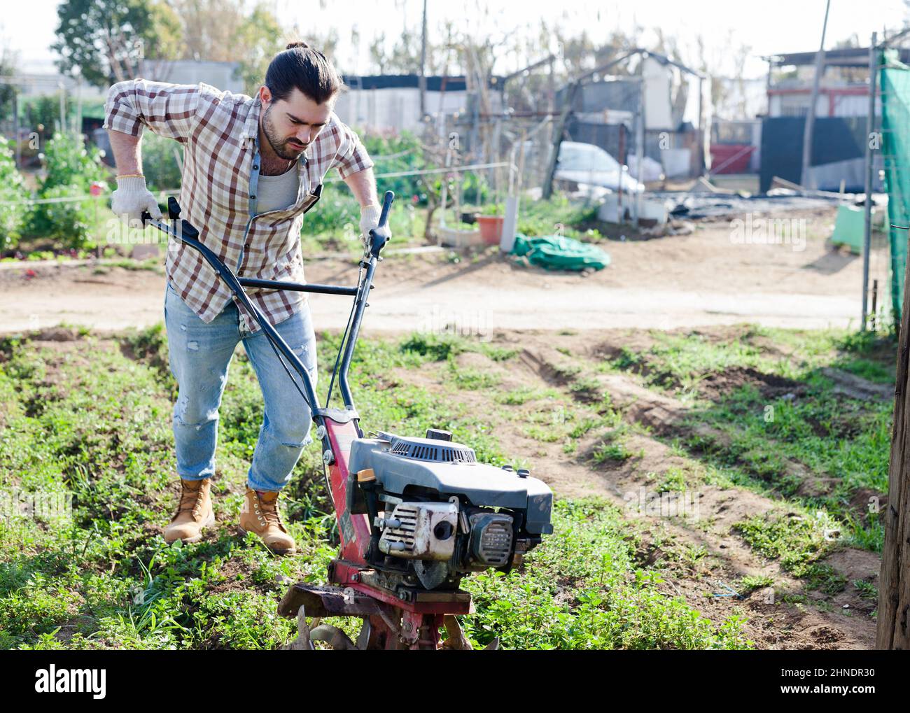 Man professional gardener using plow at land with green grass in garden ...