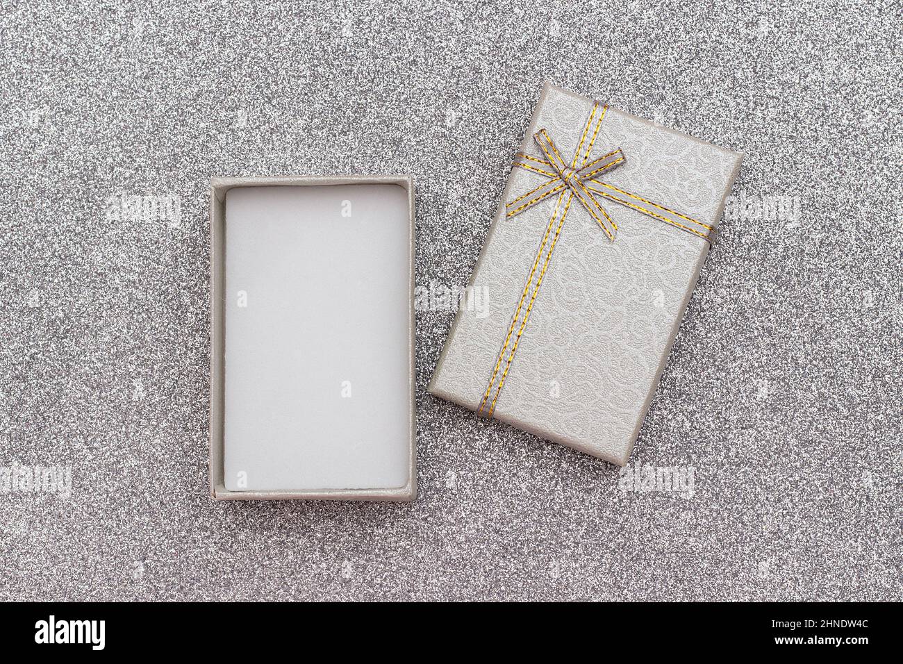 Open gray gift box with bow on silver shiny background in minimal style ...