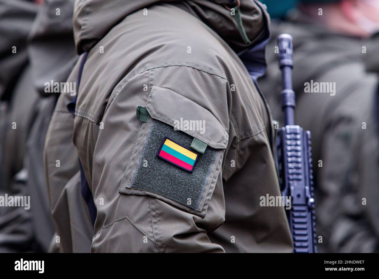 Lithuanian NATO soldier holding gun. Close up shot of Lithuania flag on ...