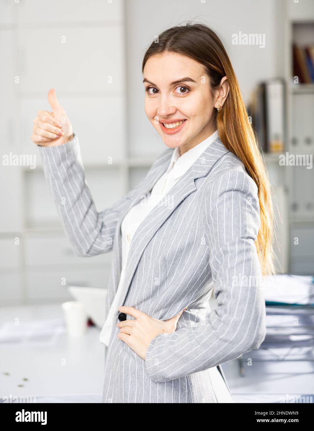 Woman office worker making thumb up gesture Stock Photo - Alamy