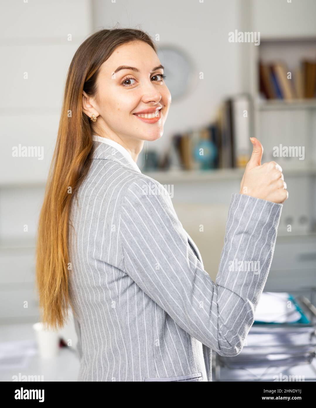 Woman office worker making thumb up gesture Stock Photo - Alamy