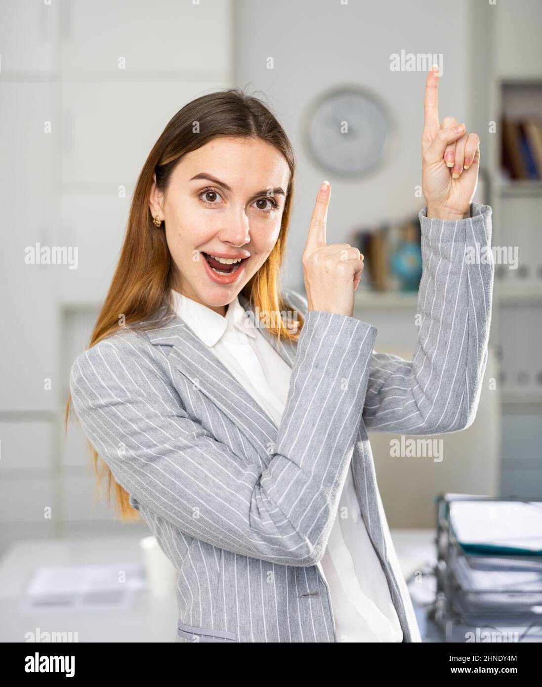 Female office manager standing and pointing finger up Stock Photo - Alamy