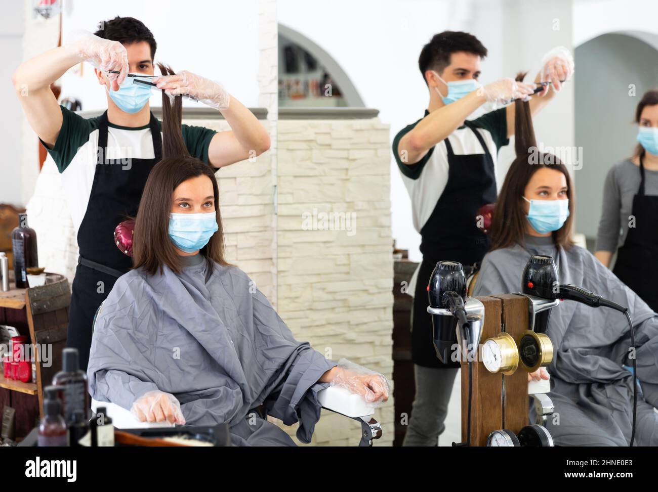 Man doing haircut for woman in salon using face masks Stock Photo - Alamy