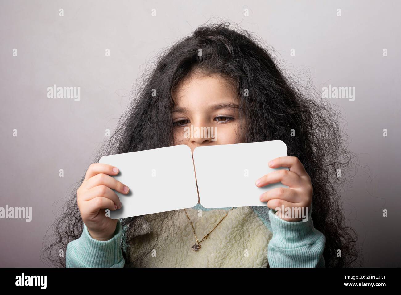Little girl portrait holding two flash card in front of face ...