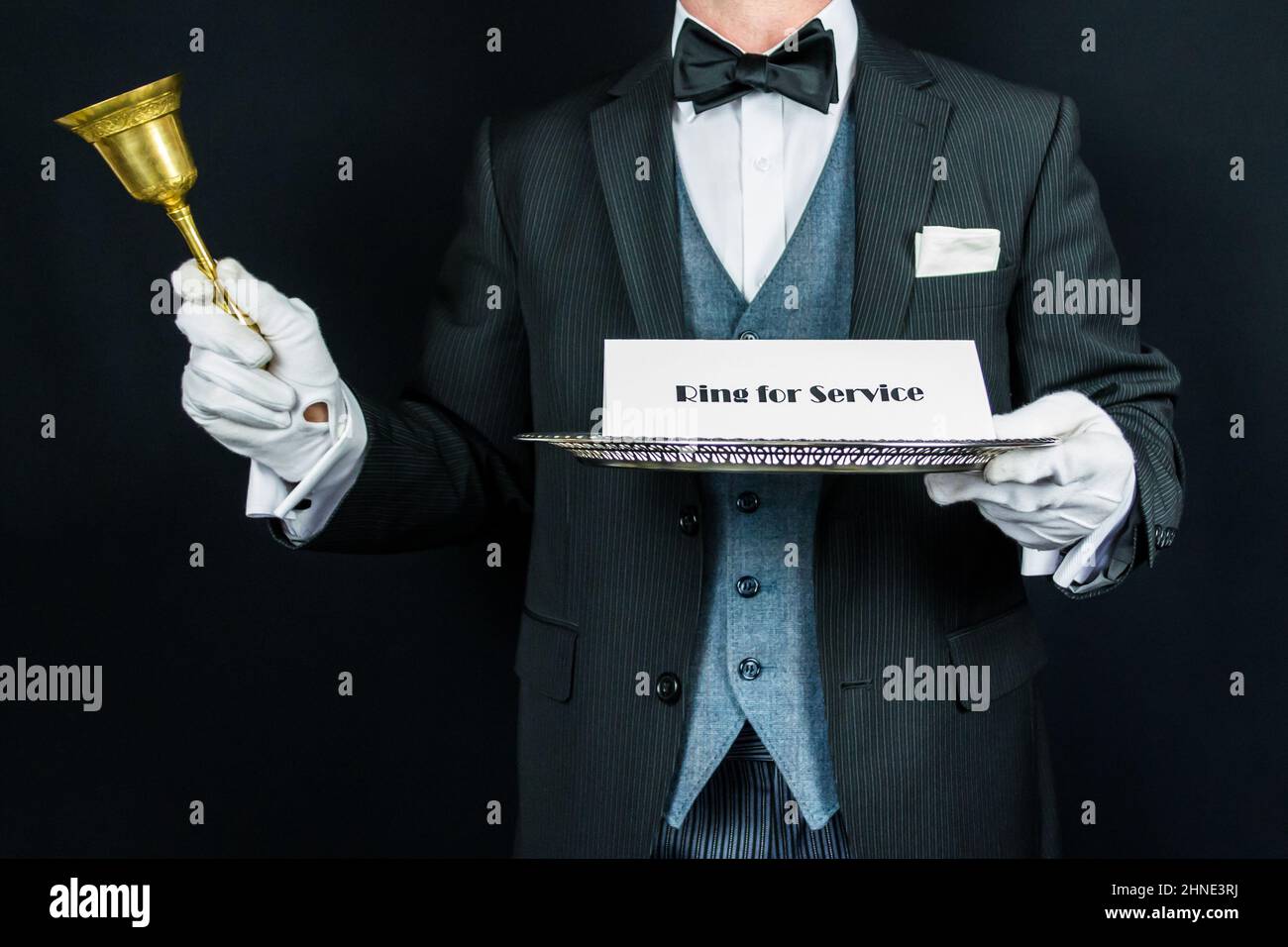 Butler in Formal Suit and White Gloves Holding Gold Bell and Sign on ...