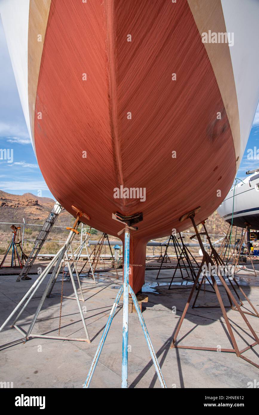 Large red hull and keel of a sailboat on boat stands in a boat yard ...