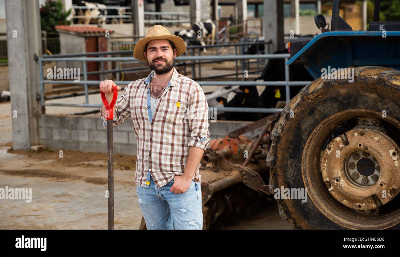 Young man farmer standing near agrimotor during break at farm Stock ...