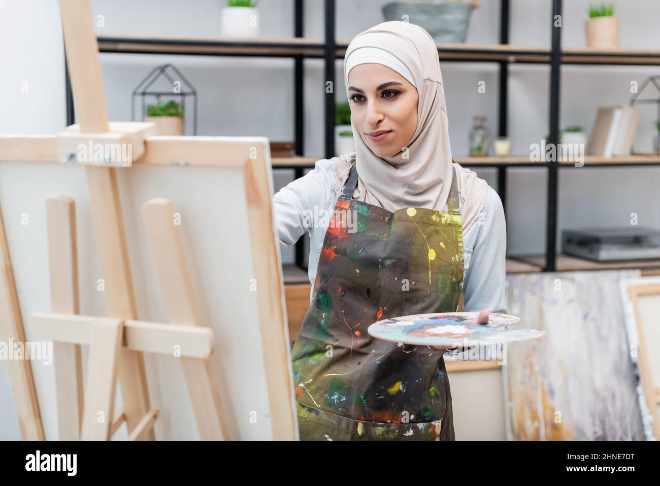 young muslim woman in canvas and hijab drawing on canvas at home Stock ...