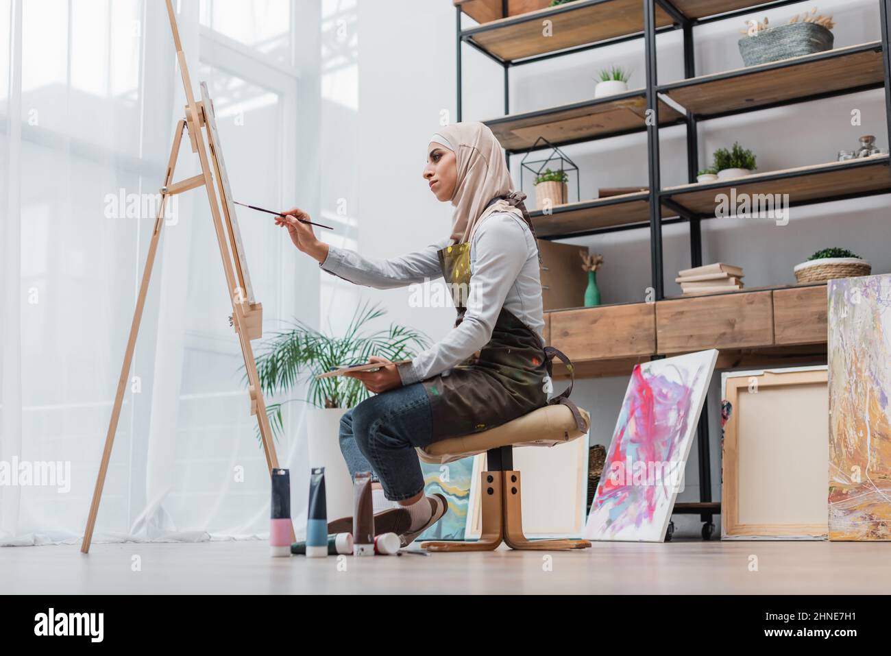 side view of muslim woman drawing on easel in home studio Stock Photo ...