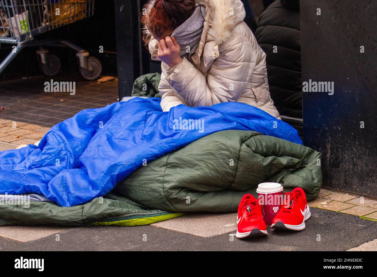 Homeless female beggar sleeping rough with expensive red Nike trainers ...