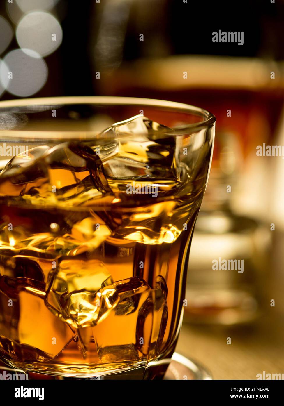 Whisky on the rocks with defocused string of lights in the background ...