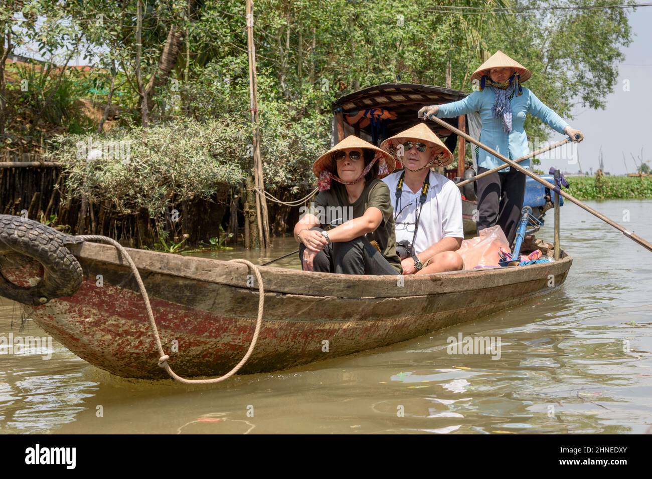 Vietnamese woman rowing tourists along the Mekong River in a ...