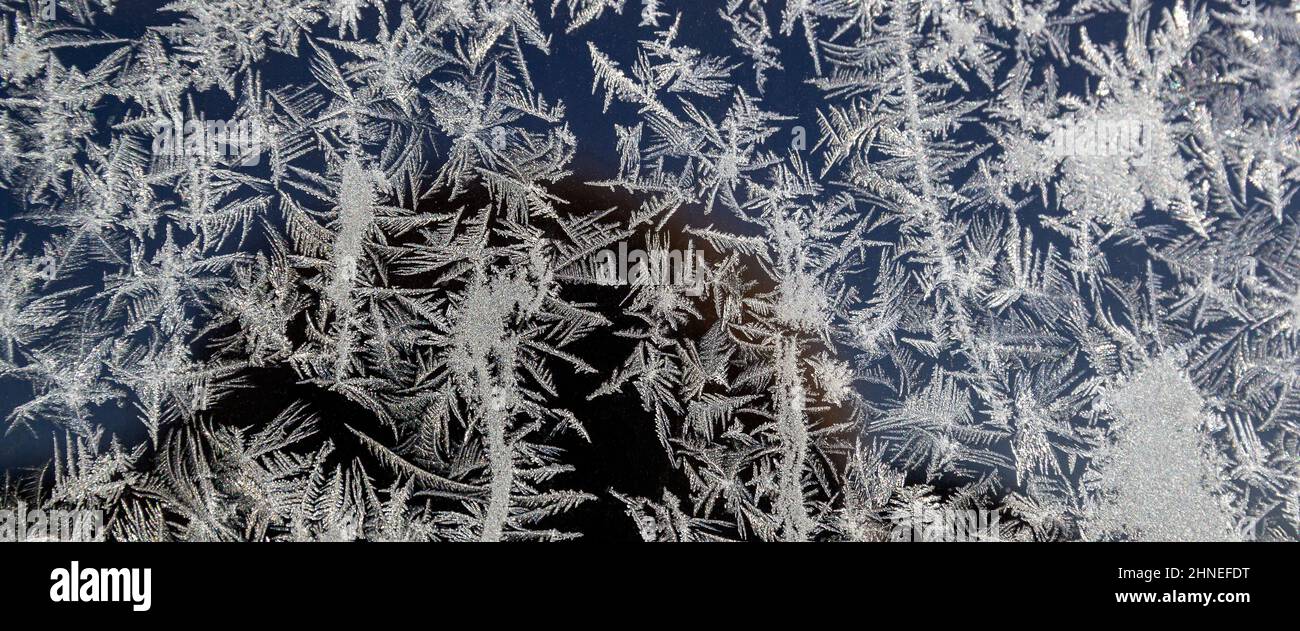 Melting ice running down a window pane, Closeup of frozen window pane surface with ice crystals ...