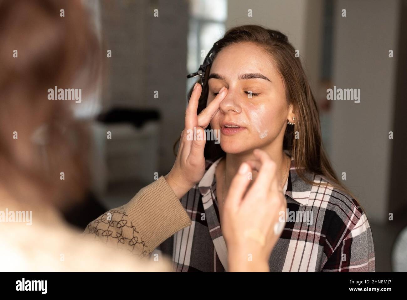 Make-up artist applies make-up base on girl's face. High quality photo ...
