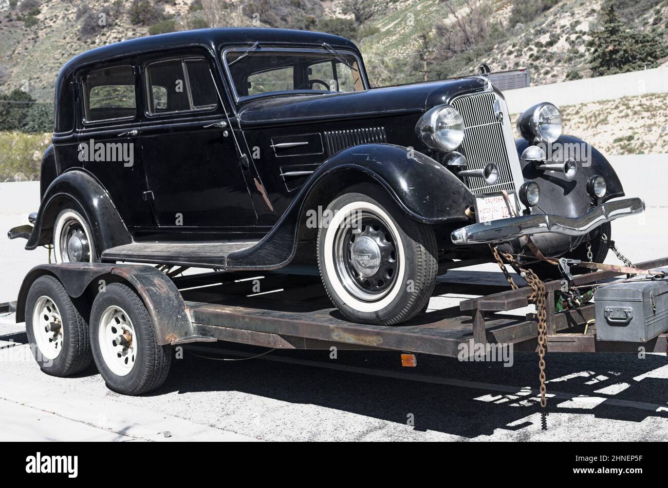 Vintage black automobile shown loaded on a trailer in the Mojave Desert ...