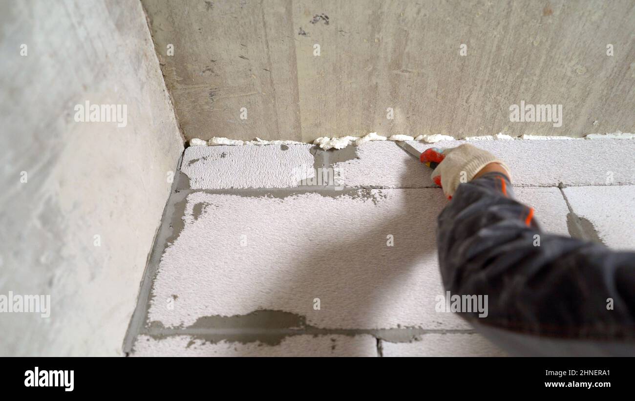 A worker builds a wall of white blocks inside the apartment ...