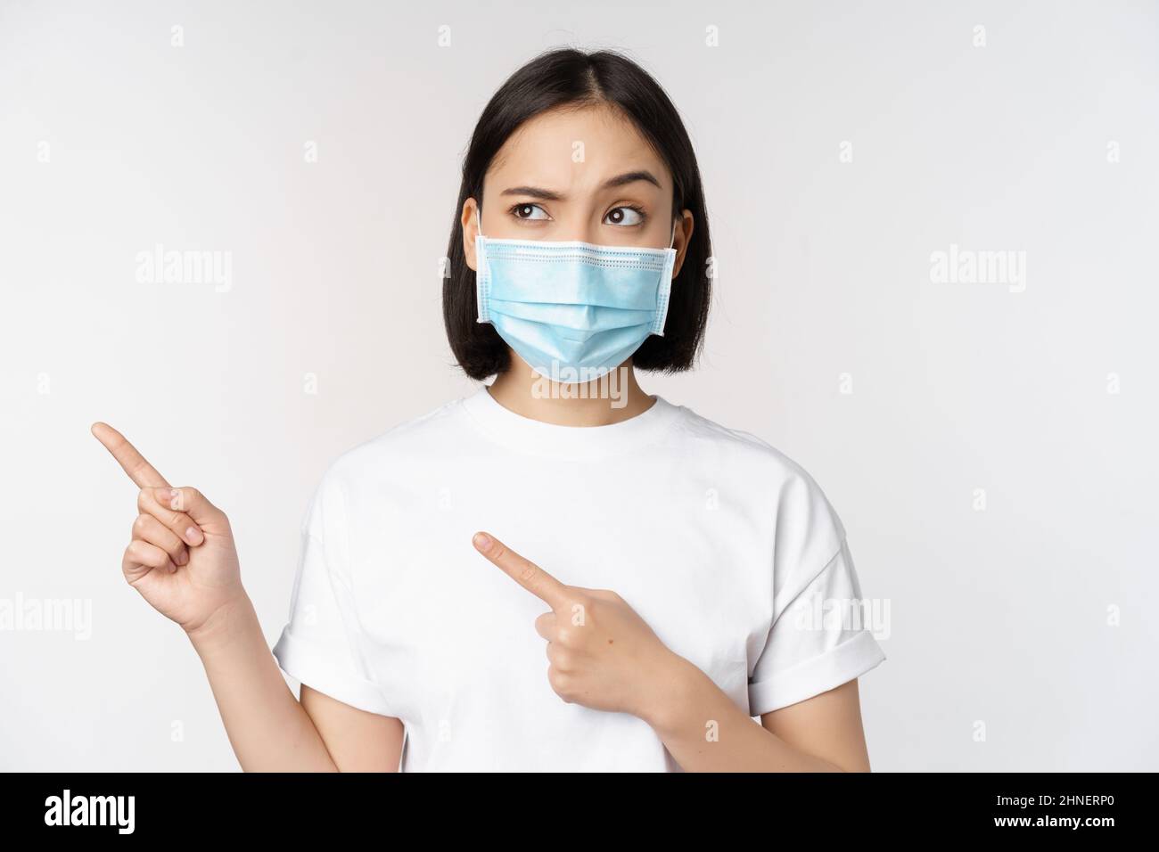 Image of asian woman in medical mask from covid, looking confused left ...