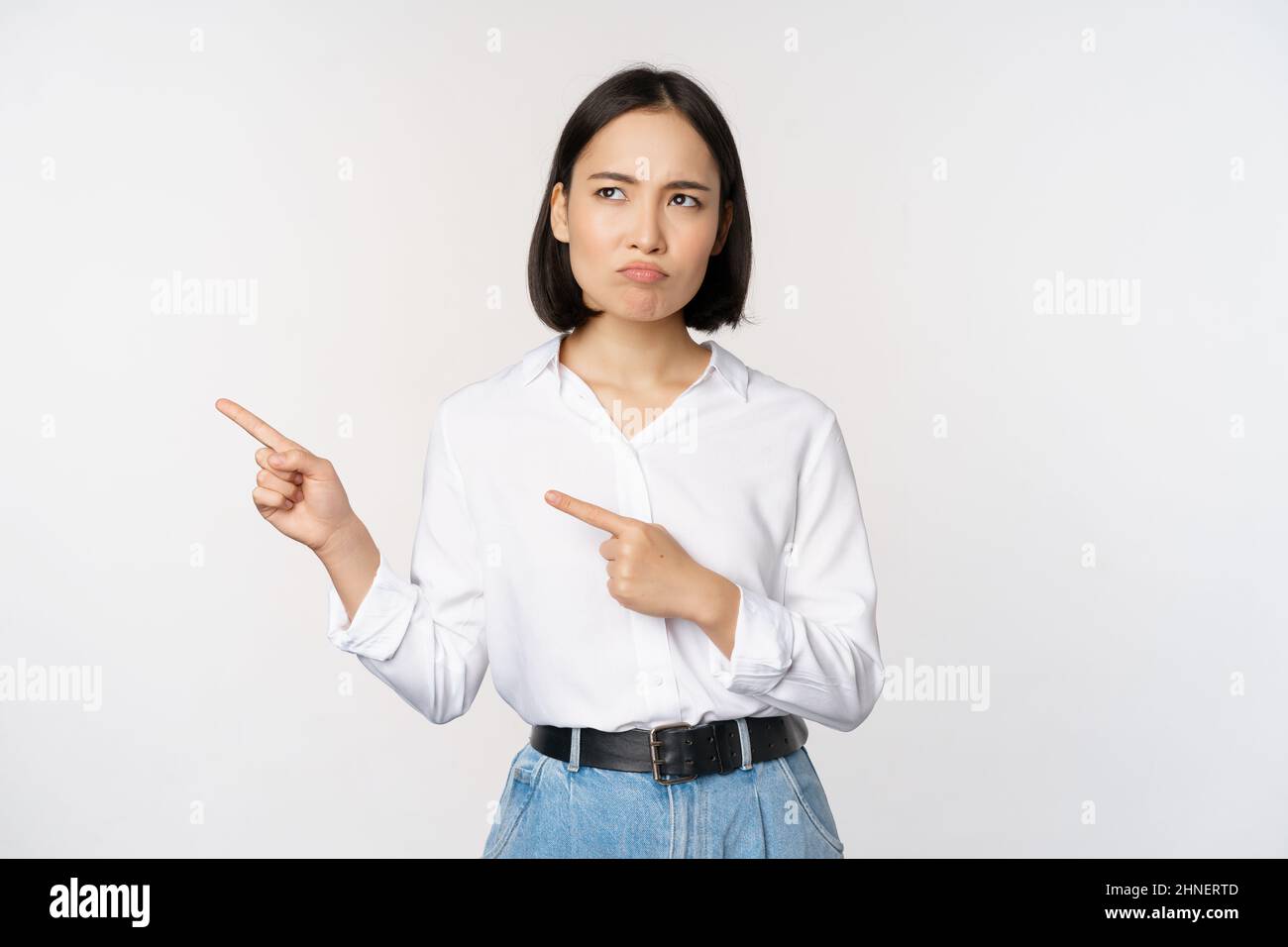 Disappointed, sad young asian woman pointing and looking left with ...
