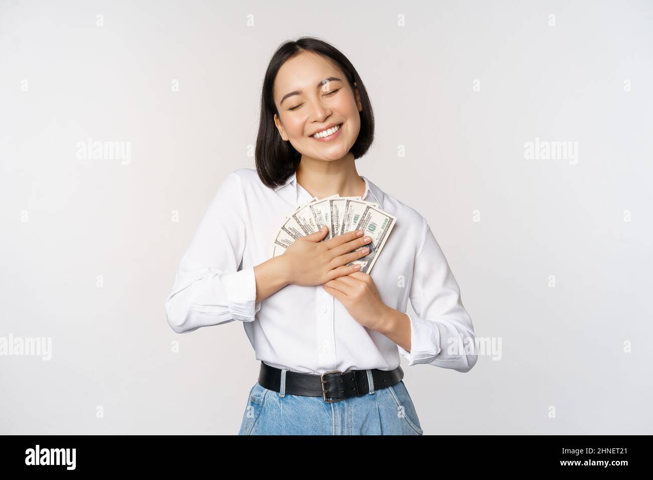 Happy asian woman hugging money dollars and smiling satisfied, standing ...