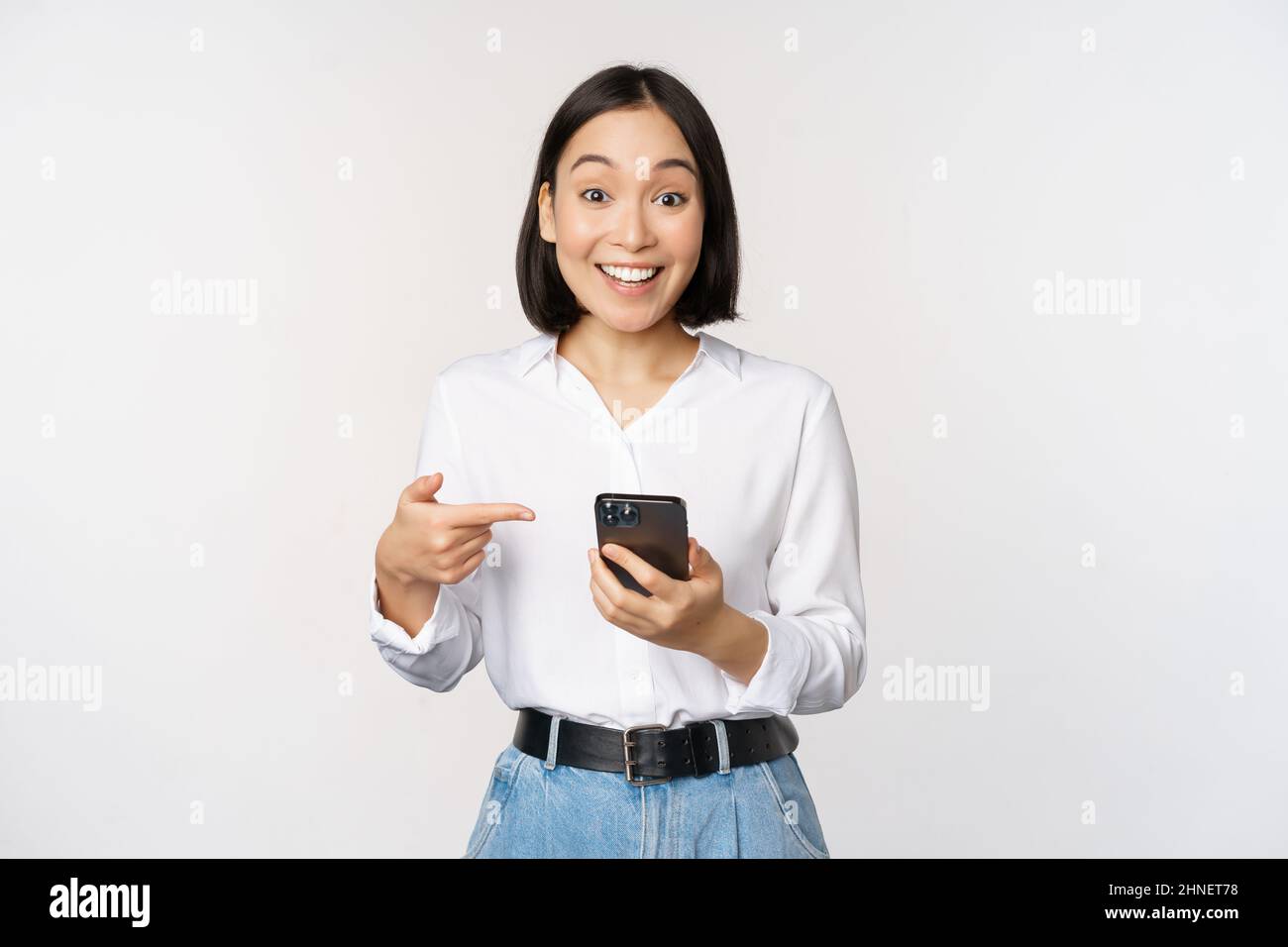 Amazed girl talking about smartphone app, pointing at phone while ...