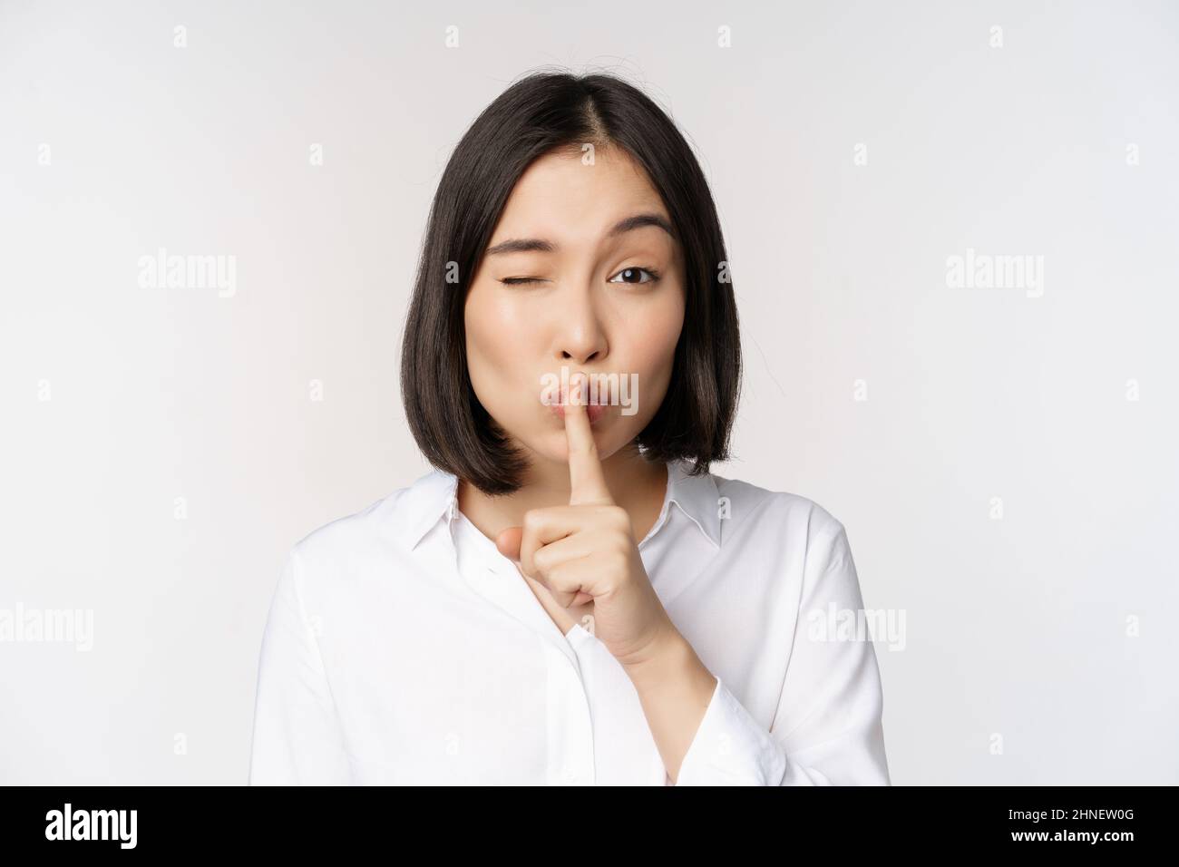 Close up portrait of young asian woman making hush, shhh shush sign ...