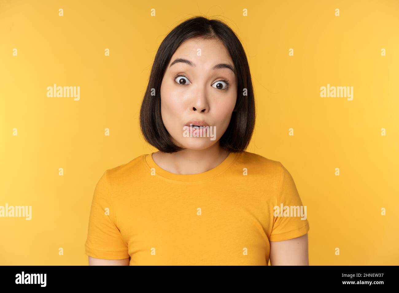 Close up portrait of asian girl showing surprised reaction, raising ...