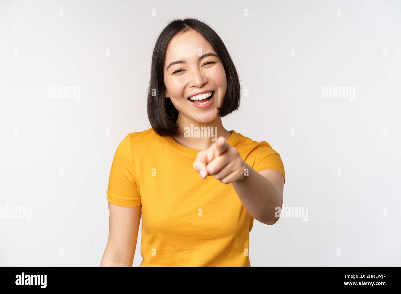 Happy beautiful asian woman laughing, pointing finger at camera and ...