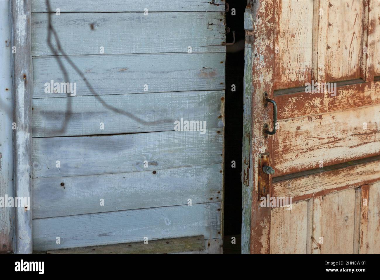 a damaged unlocked door of old wooden house or shed, outdoor cropped ...