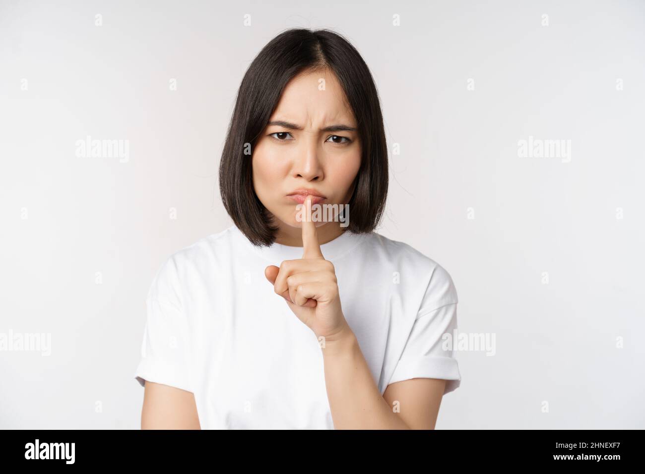 Angry asian girl shushing, keep quiet, taboo silence gesture, press ...